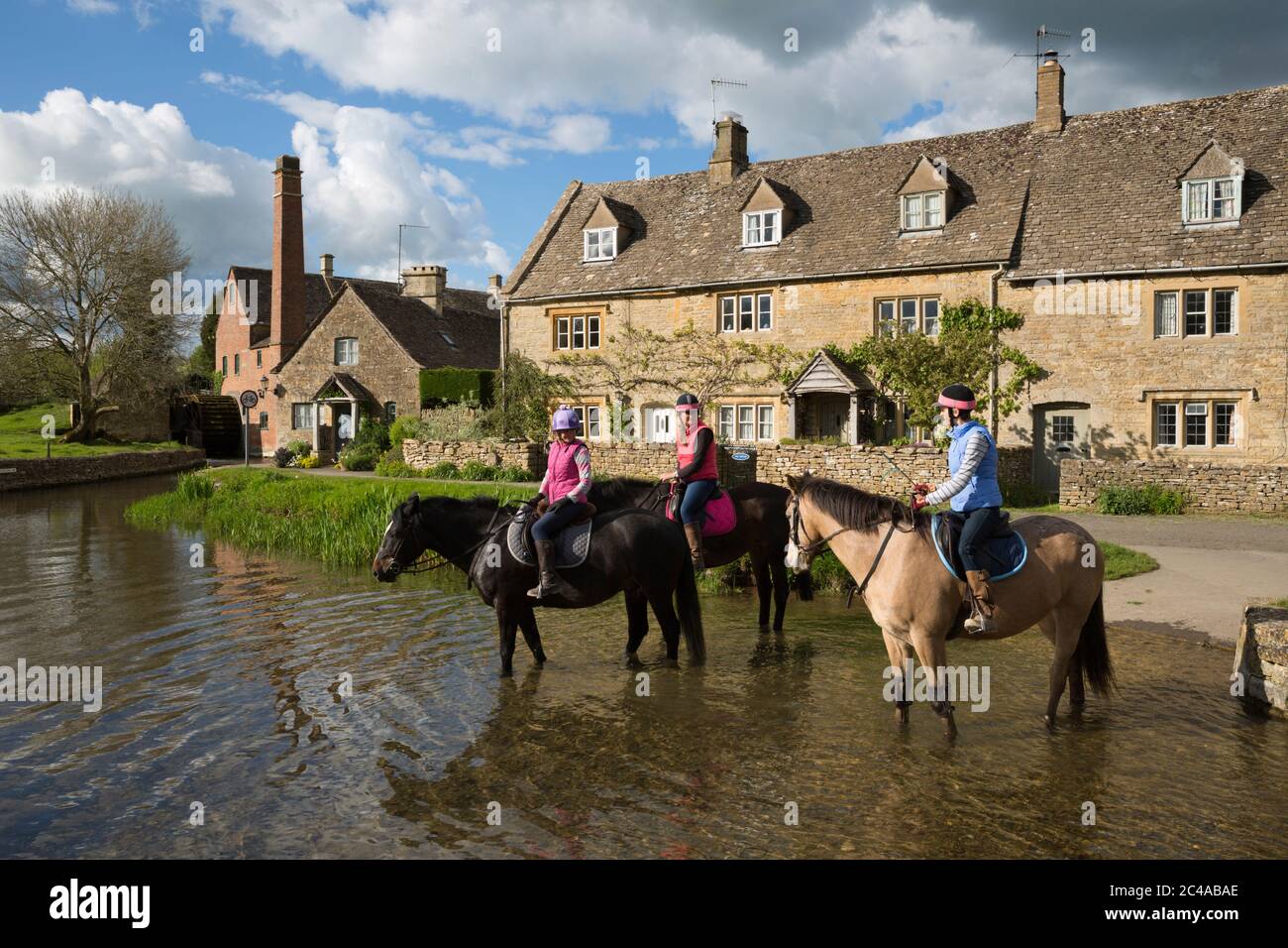 Horses in the River Eye with The Old Mill Museum and cotswold cottages ...