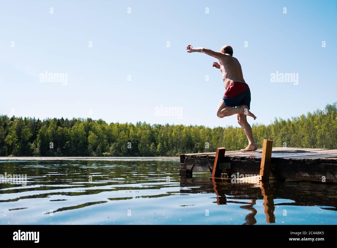 Man jump to lake water having fun during vacation Stock Photo - Alamy