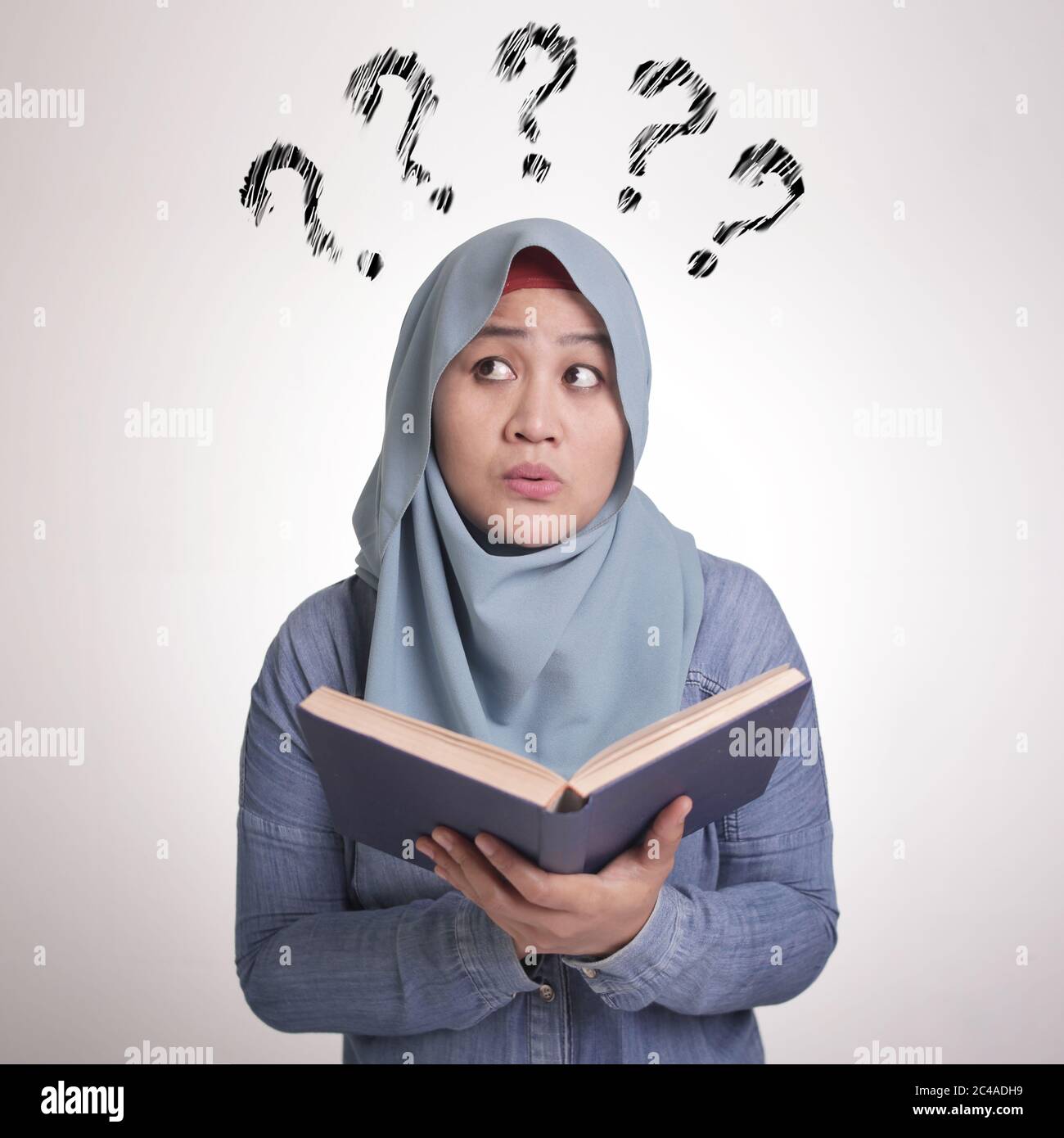 Portrait of young Asian muslim woman wearing hijab holding book with ...