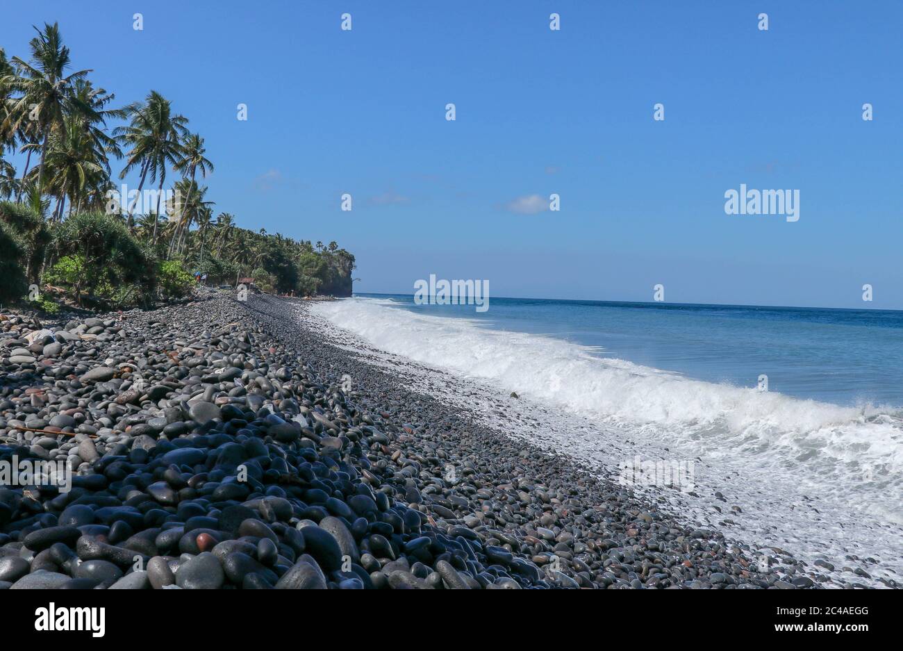 Tropical beach with black pebbles. The island of Bali with a rocky ...