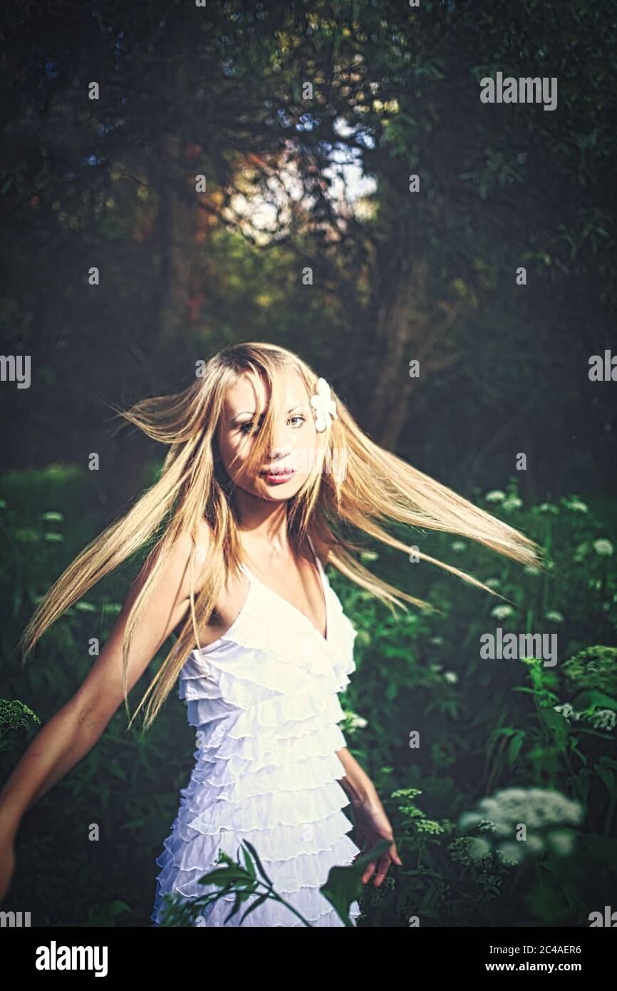 Lady in white dress dancing in the woods with her hair fly in the air ...
