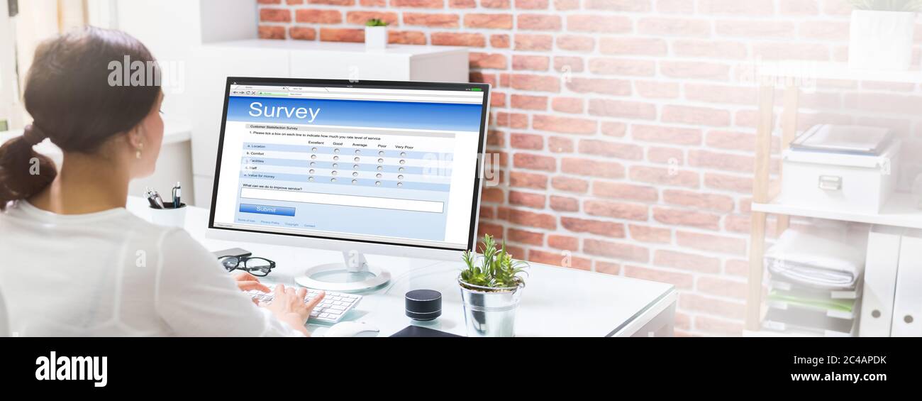 Young Businesswoman Filling Online Survey Form On Computer At Desk ...