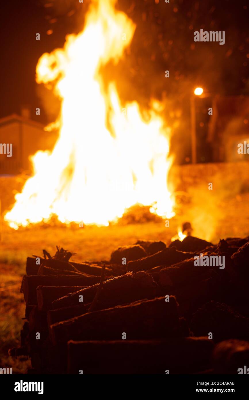 Pile of logs with a giant bonfire burning on the background Stock Photo ...