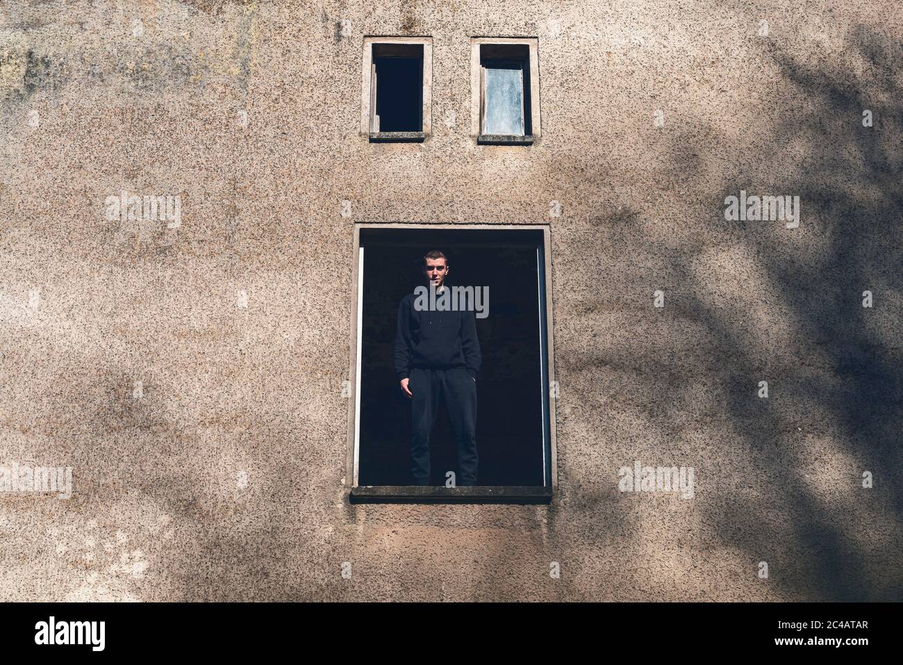 smiling young man stands in an open window of a house Stock Photo - Alamy