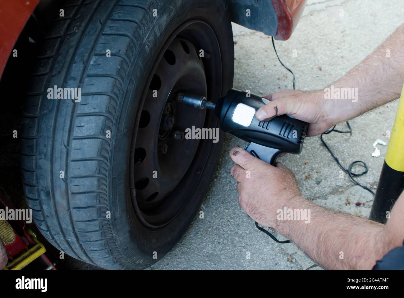 Mechanic changing wheel on car with impact wrench, man with electric ...