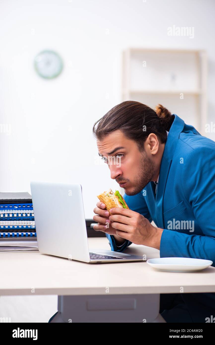 Young employee having breakfast at workplace Stock Photo - Alamy