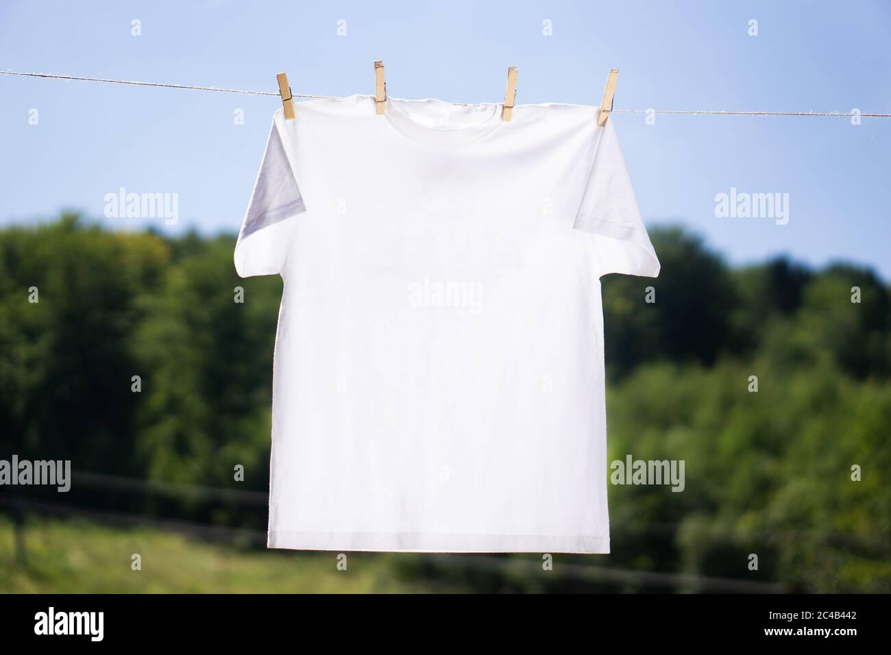 White t-shirt mock-up hanging on the rope with clothespins on summer ...