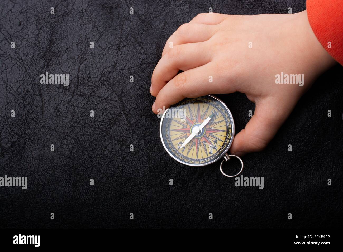 Hand is holding a magnetic compass on black background Stock Photo - Alamy
