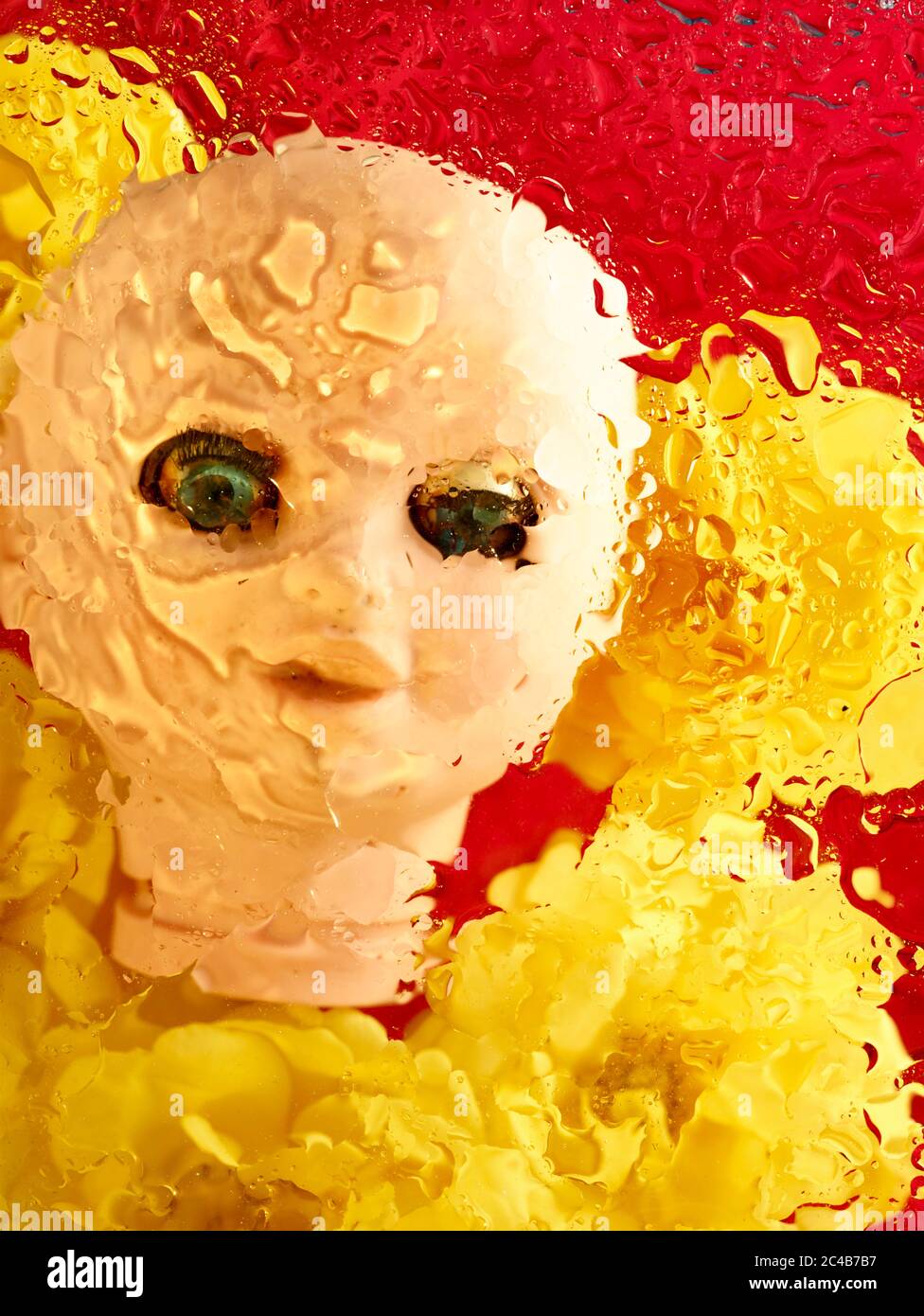 Decapitated dolls head and yellow roses drowning under water droplets ...