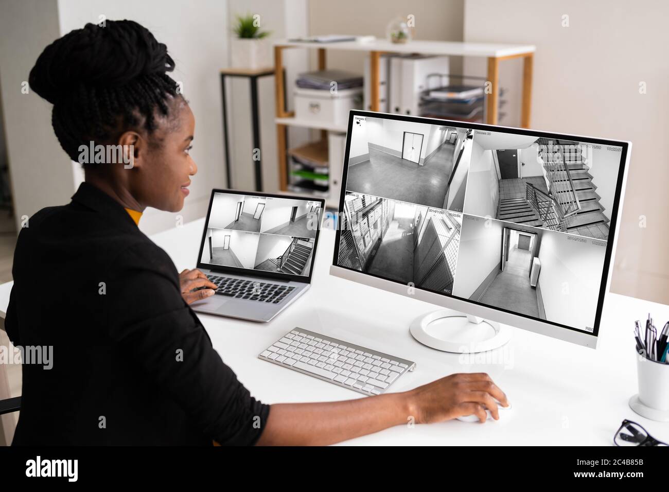 Businesswoman Watching CCTV Footage Of Office Interior On Computer At ...
