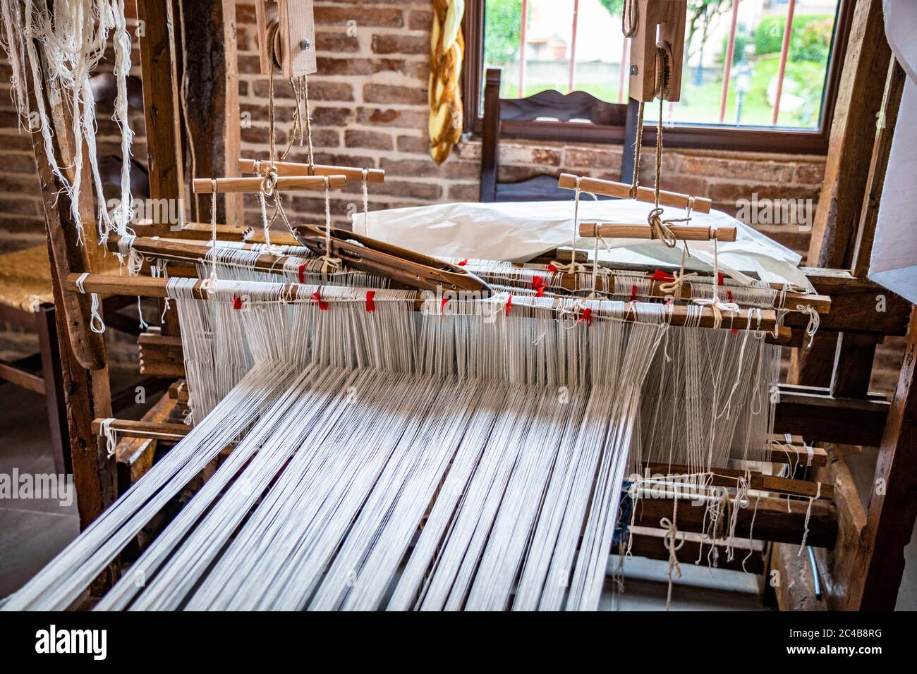 Close up of an ancient wooden weaving loom with twisted threads to ...