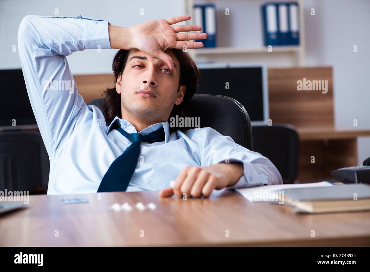 The young man having problems with narcotics at workplace Stock Photo ...