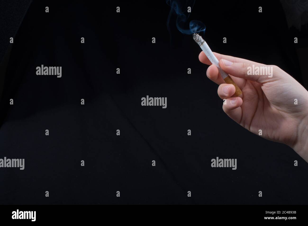 Hand is holding smoking cigarette with smoke around Stock Photo - Alamy