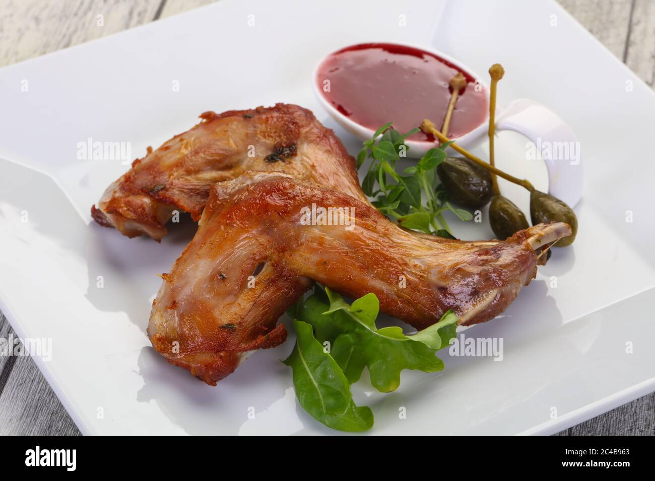 Roasted rabbit legs with cowberry sauce Stock Photo - Alamy
