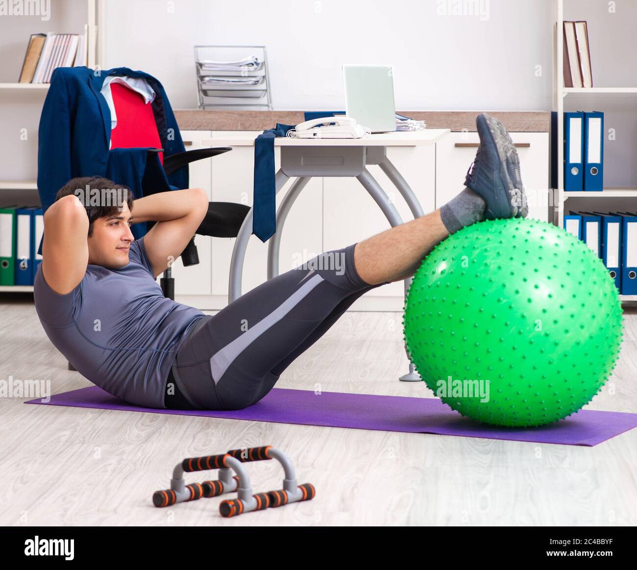 The young male employee exercising in the office Stock Photo - Alamy