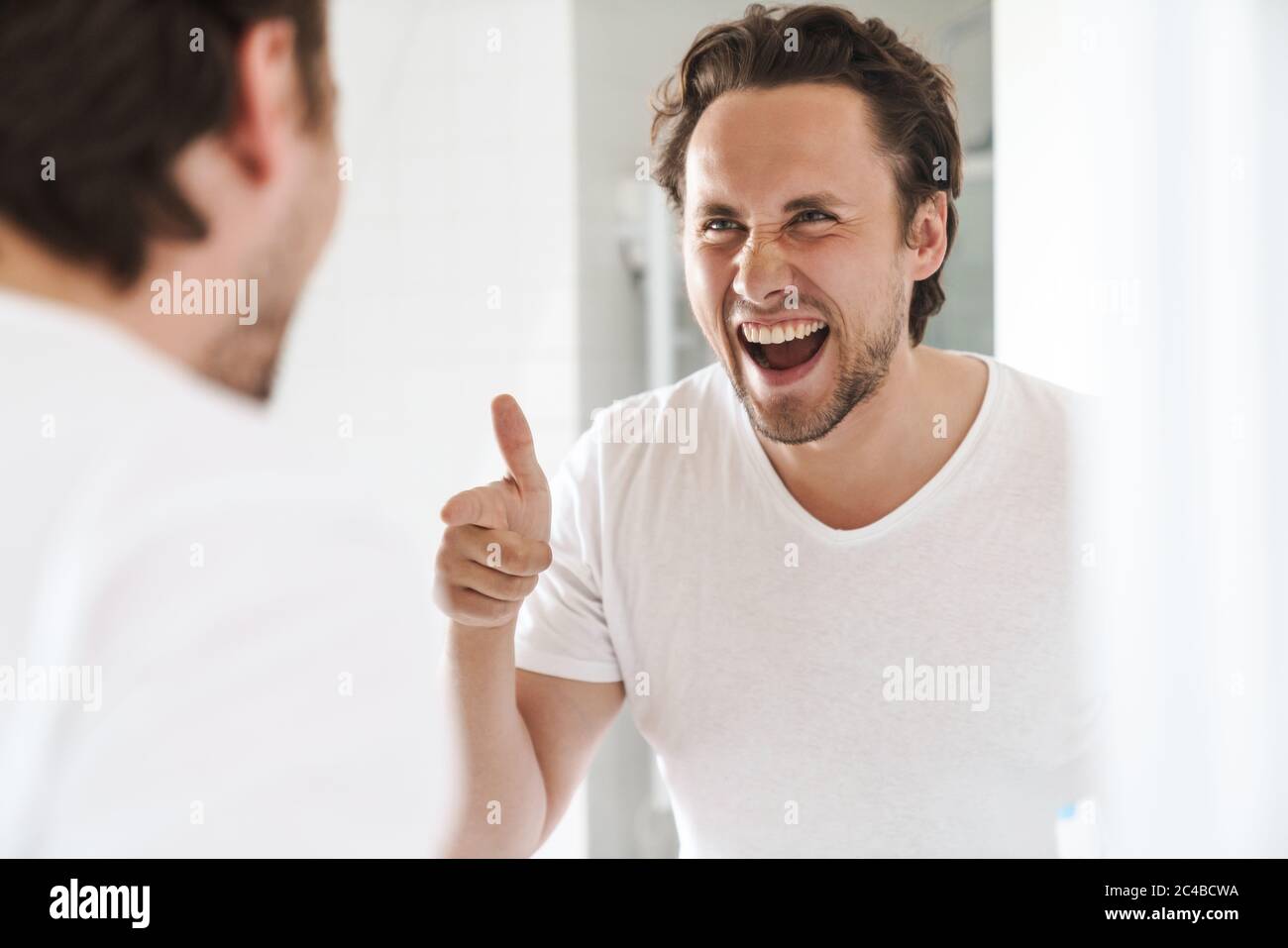 Attractive happy confident young man standing in front of the bathroom ...