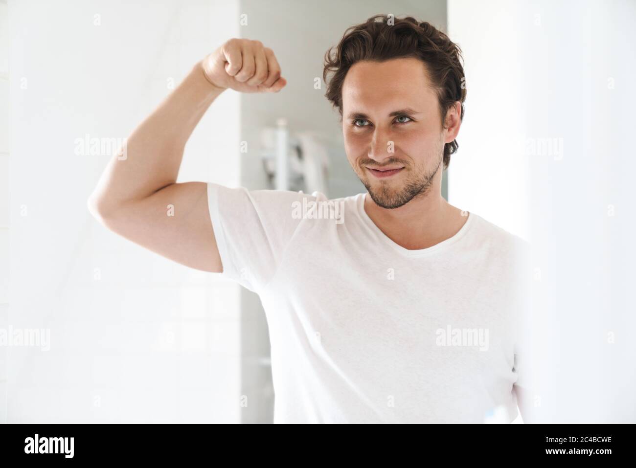 Attractive happy confident young man standing in front of the bathroom ...