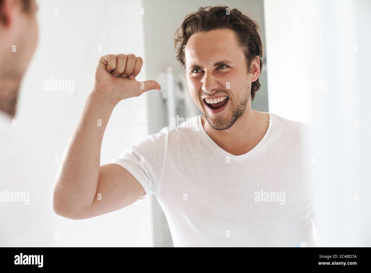 Attractive happy confident young man standing in front of the bathroom ...