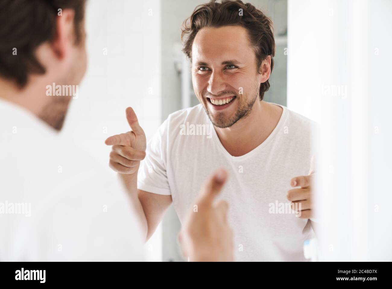 Attractive happy confident young man standing in front of the bathroom ...