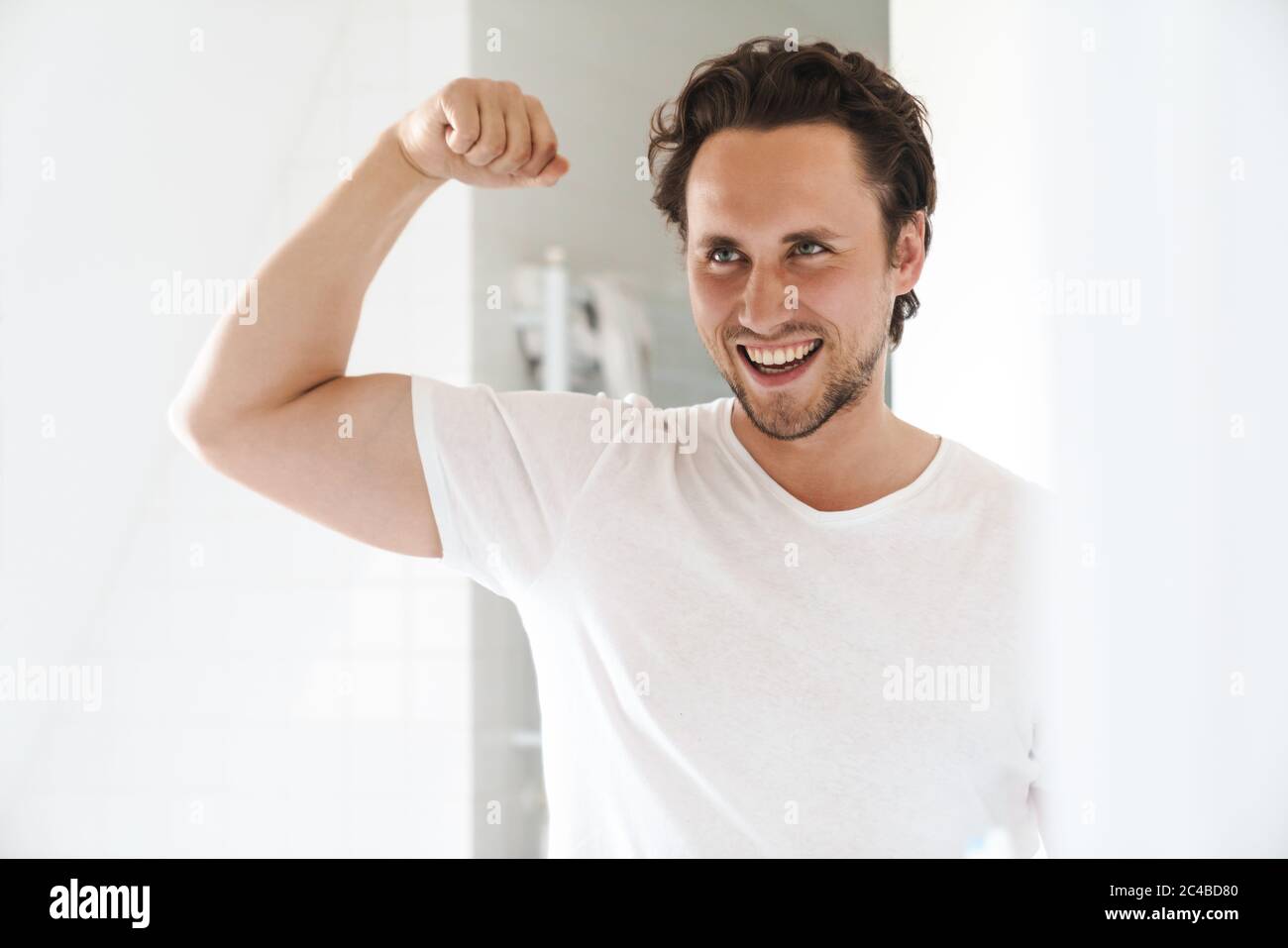 Attractive happy confident young man standing in front of the bathroom ...