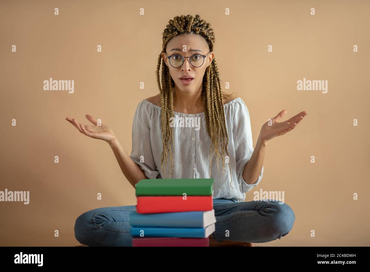 Young African American female in eyeglasses sitting on the floor in ...