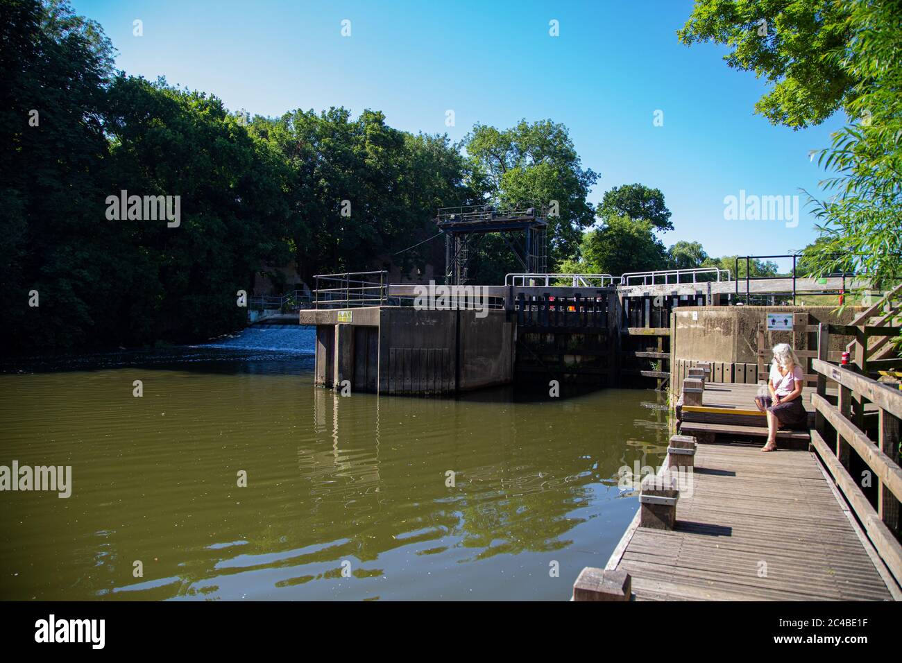 A blonde woman sits on a boardwalk looking over at the weir. Teston ...