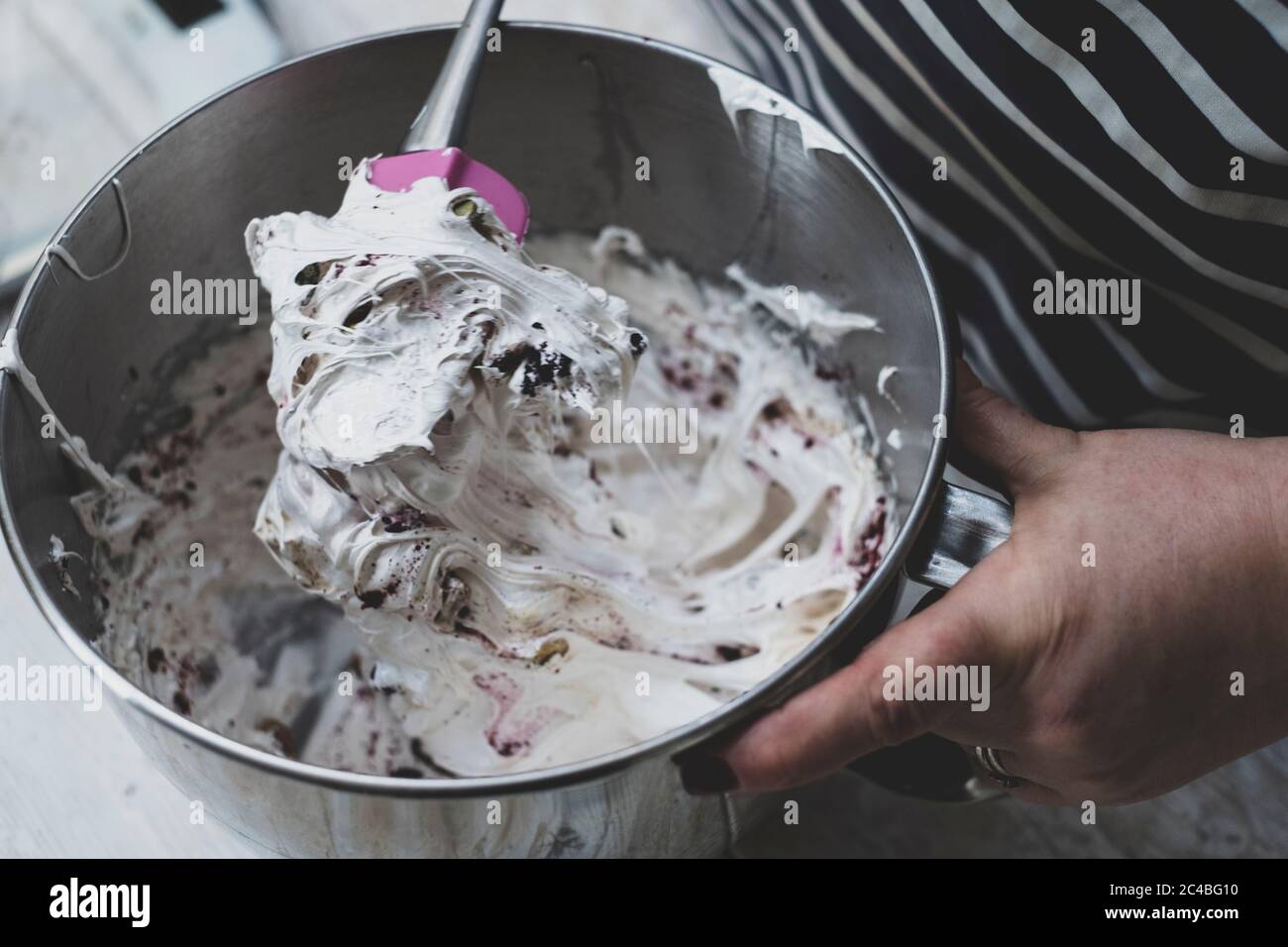 Cook folding egg whites into a baking mixture Stock Photo - Alamy