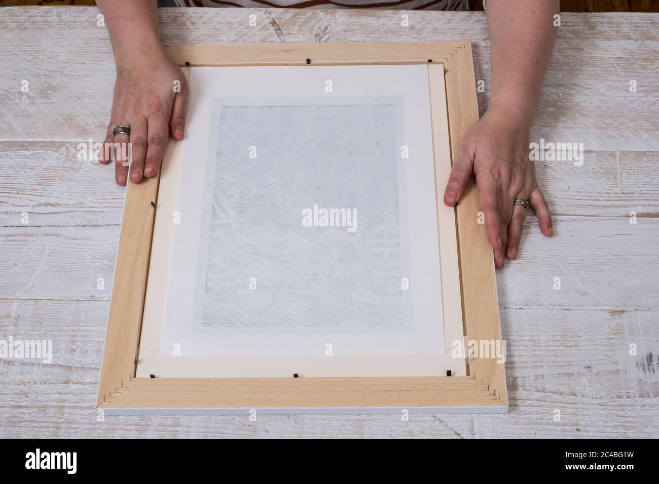 Person fitting a picture frame around a print Stock Photo - Alamy