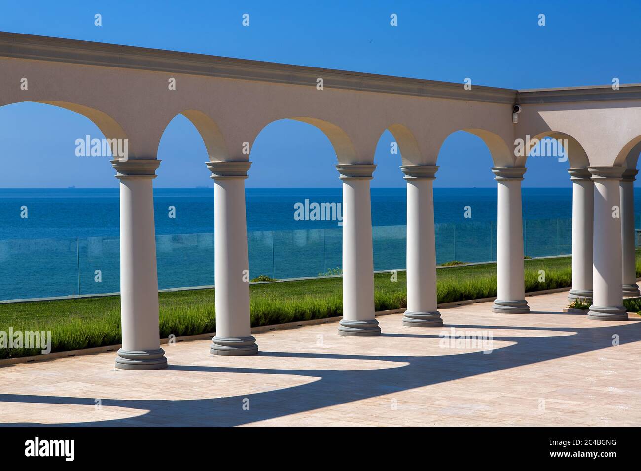 an arch with columns of white stone on sunny day and a marble floor ...