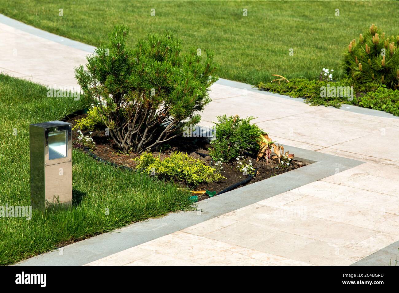 walking path of marble tiles and stone edges in the garden with a green ...