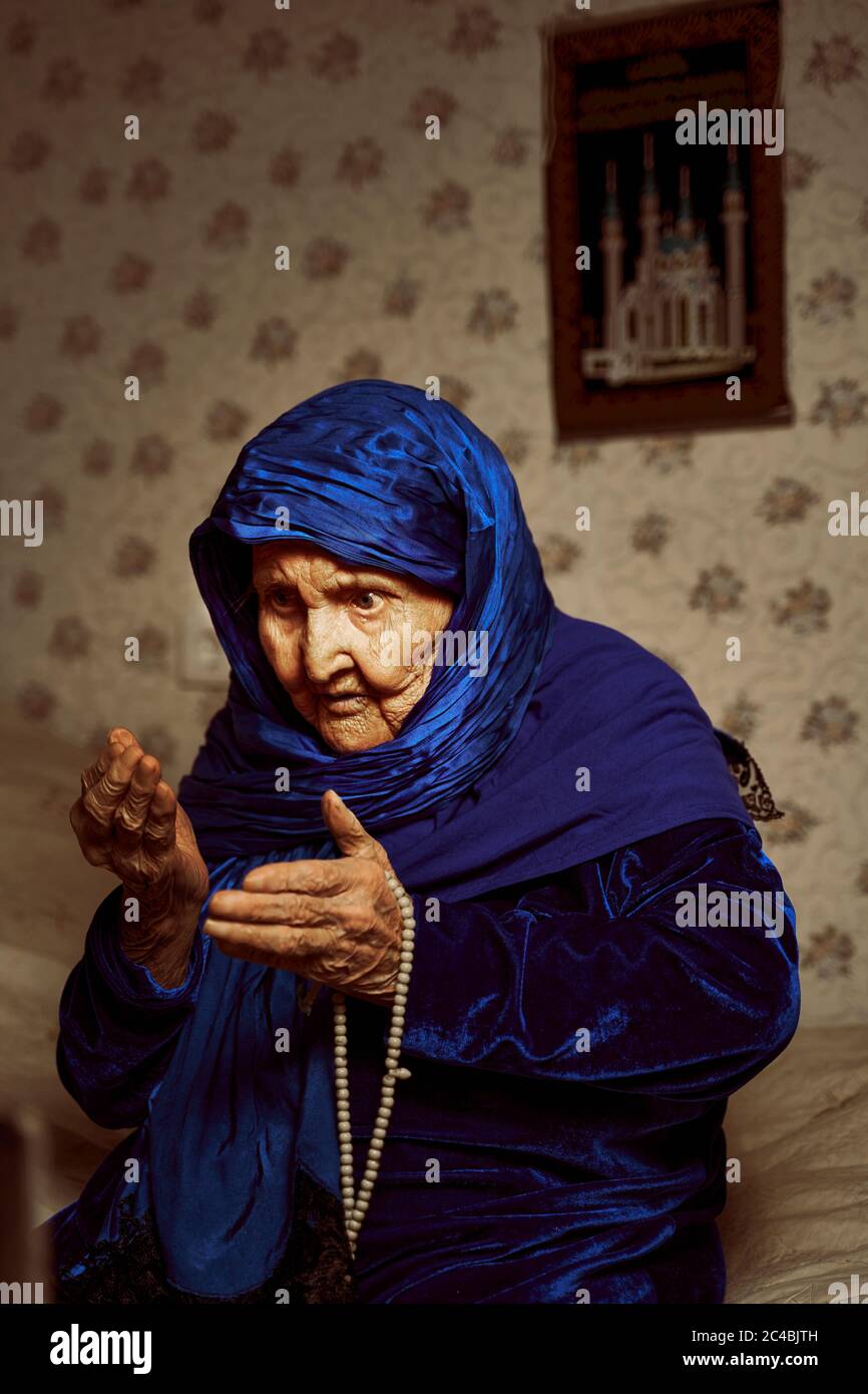 an old Muslim grandmother prays against the background of prayer with a ...