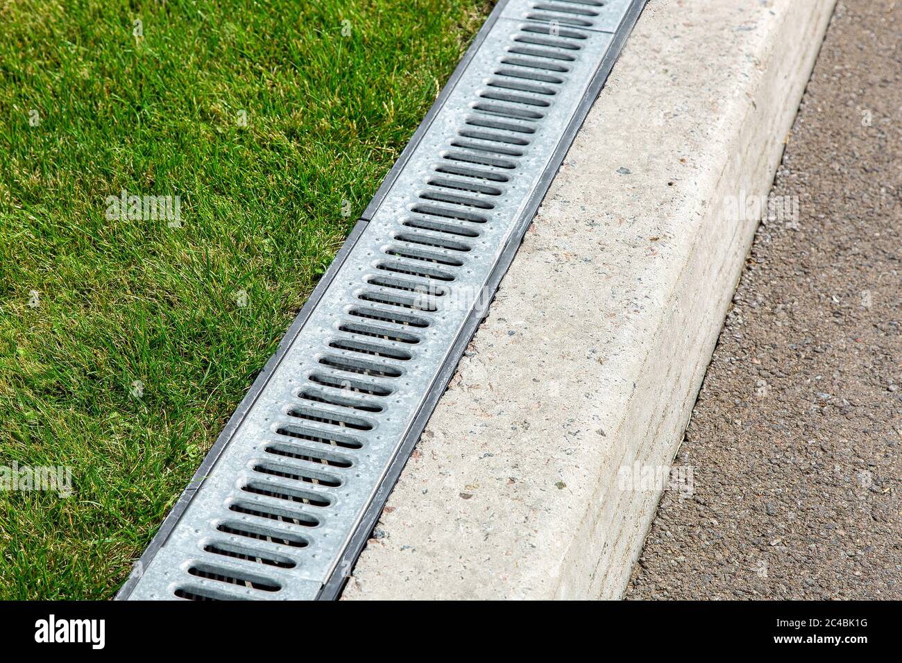iron drainage system, closeup of an iron grille along a asphalt road ...