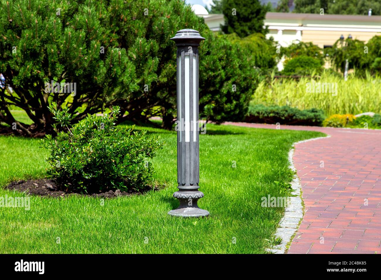 a garden ground street lantern made of iron mounted on a green lawn in ...