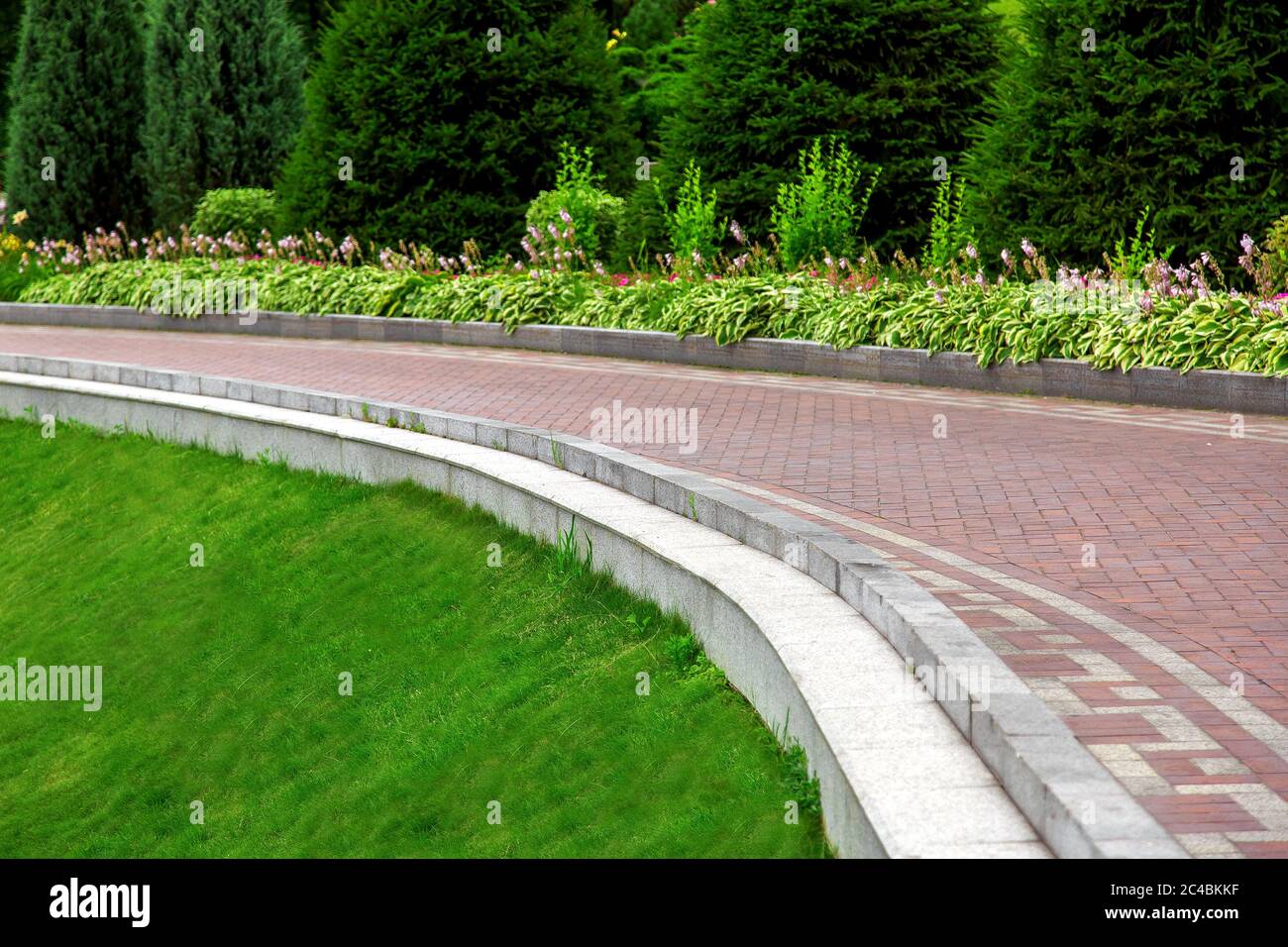the edge of the footpath reinforced by a stone curb on a slope with ...
