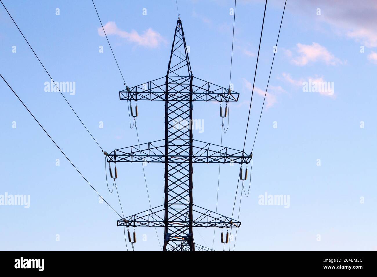 High voltage power lines in the middle of a field at sunset ...