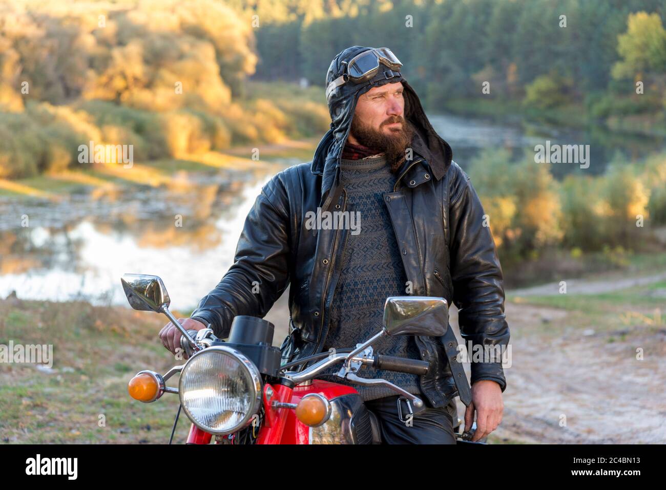 Biker in a leather jacket and helmet on a vintage retro motorcycle in ...