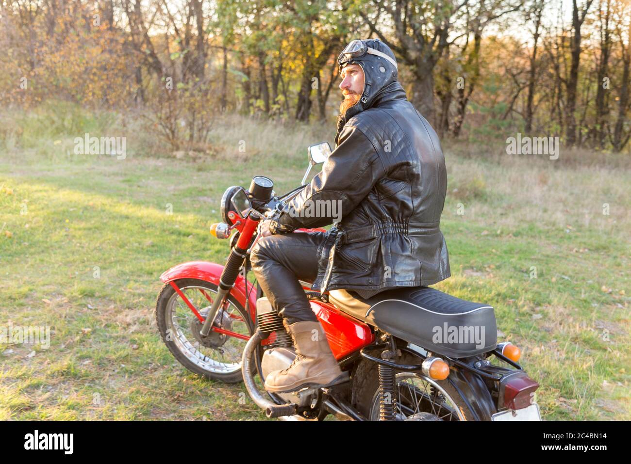 Biker in a leather jacket and helmet on a vintage retro motorcycle in ...