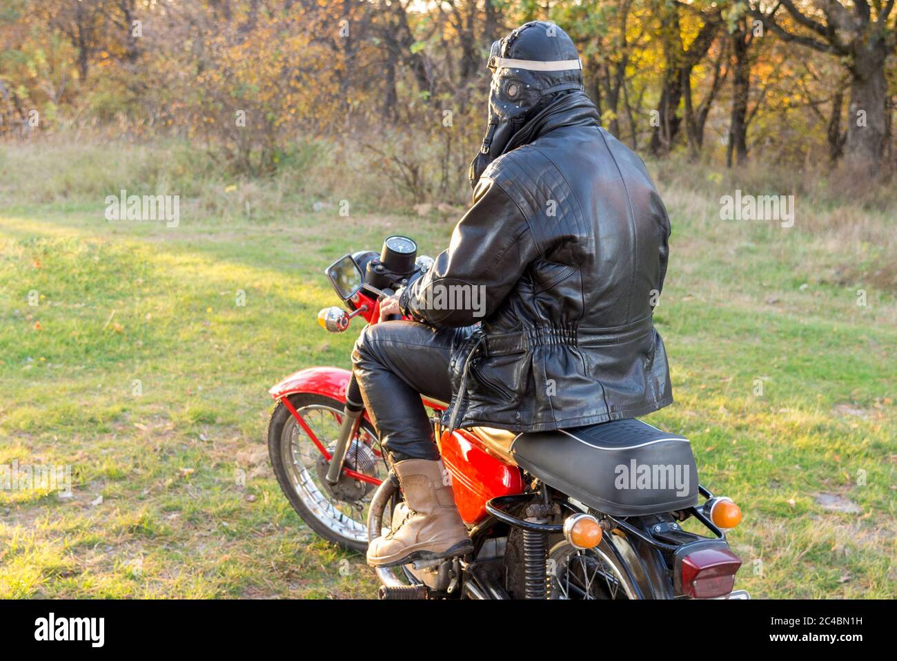 Biker in a leather jacket and helmet on a vintage retro motorcycle in ...
