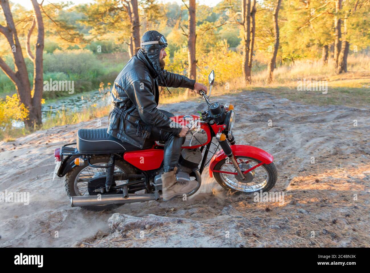 Biker in a leather jacket and helmet on a vintage retro motorcycle in ...
