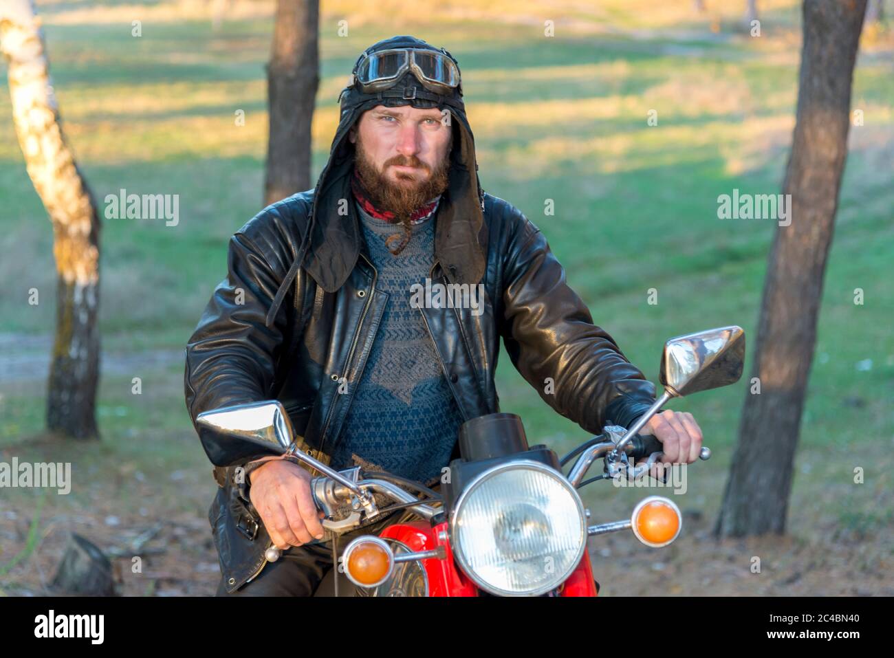 Biker in a leather jacket and helmet on a vintage retro motorcycle in ...