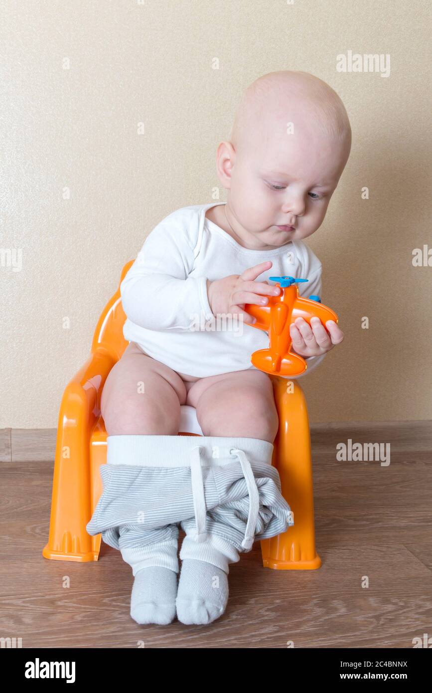 Little baby boy sitting on the pot and playing with toy airplane Stock ...