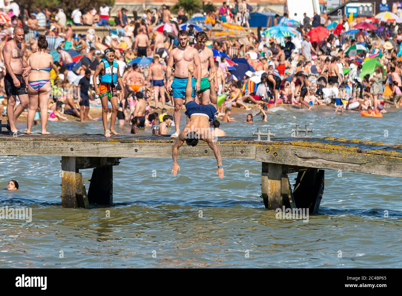 Male diving into sea. Despite the COVID-19 Coronavirus lockdown crowds ...