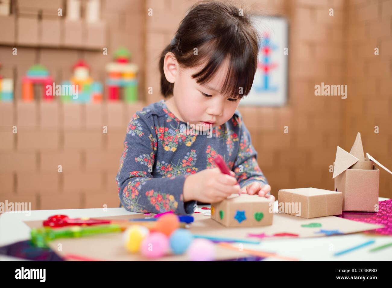 toddler girl making craft by using cardboard for homeschooling Stock ...