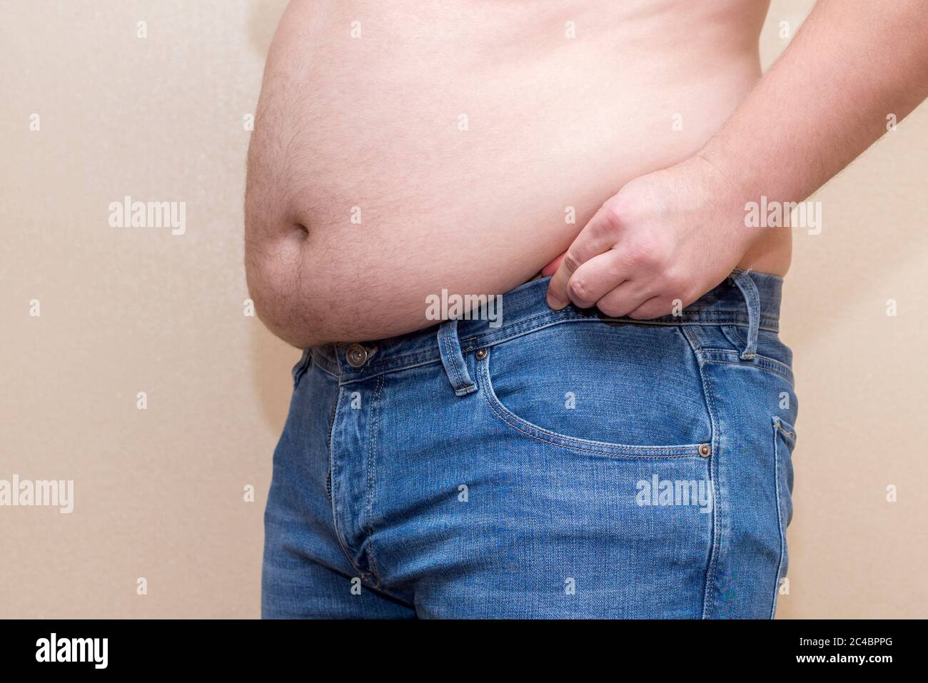 Man wearing blue jeans, fat belly closeup, the problem of overweight ...