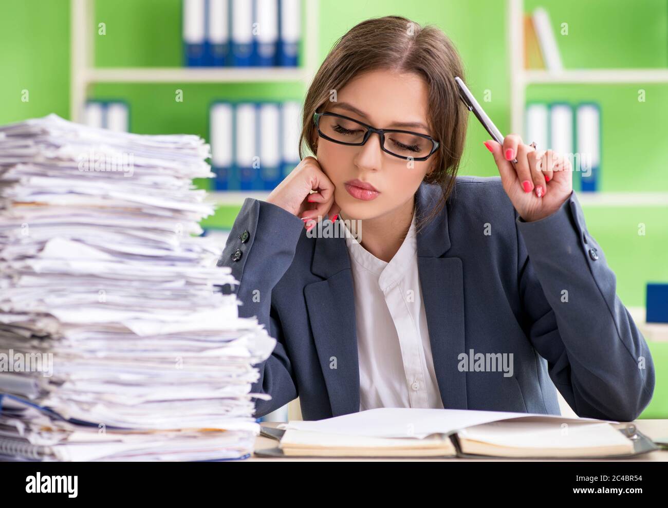The young female employee very busy with ongoing paperwork Stock Photo ...