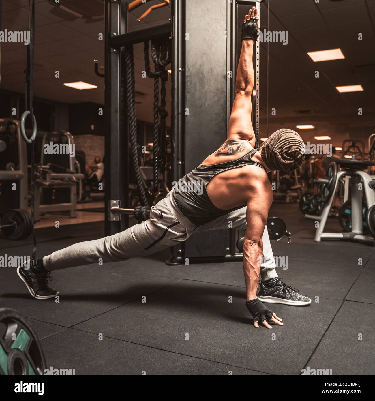 A sporty man in the gym is doing Yoga and Martial Arts exercises ...