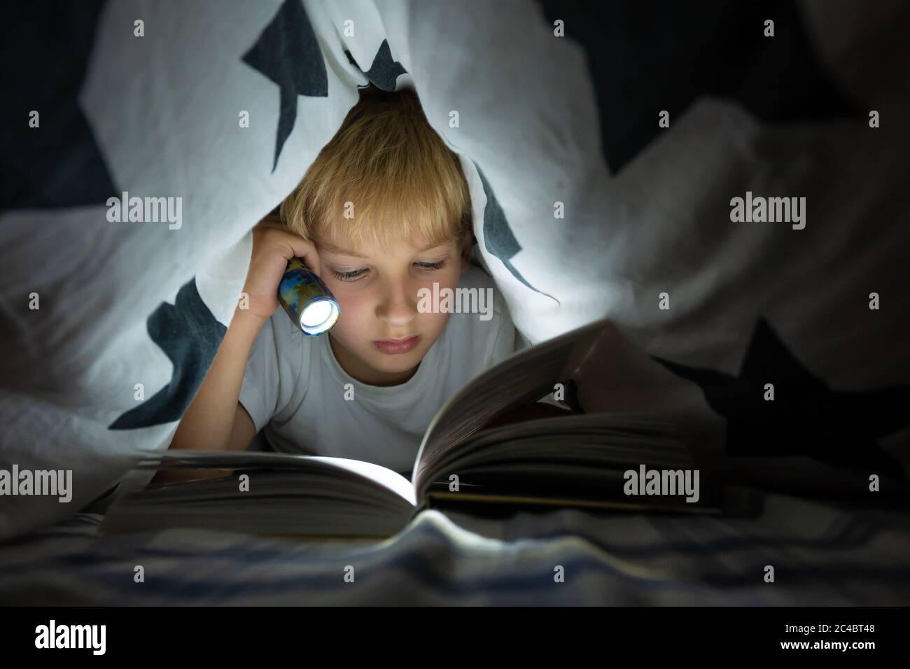 Kid reading a book with flashlight hi-res stock photography and images ...