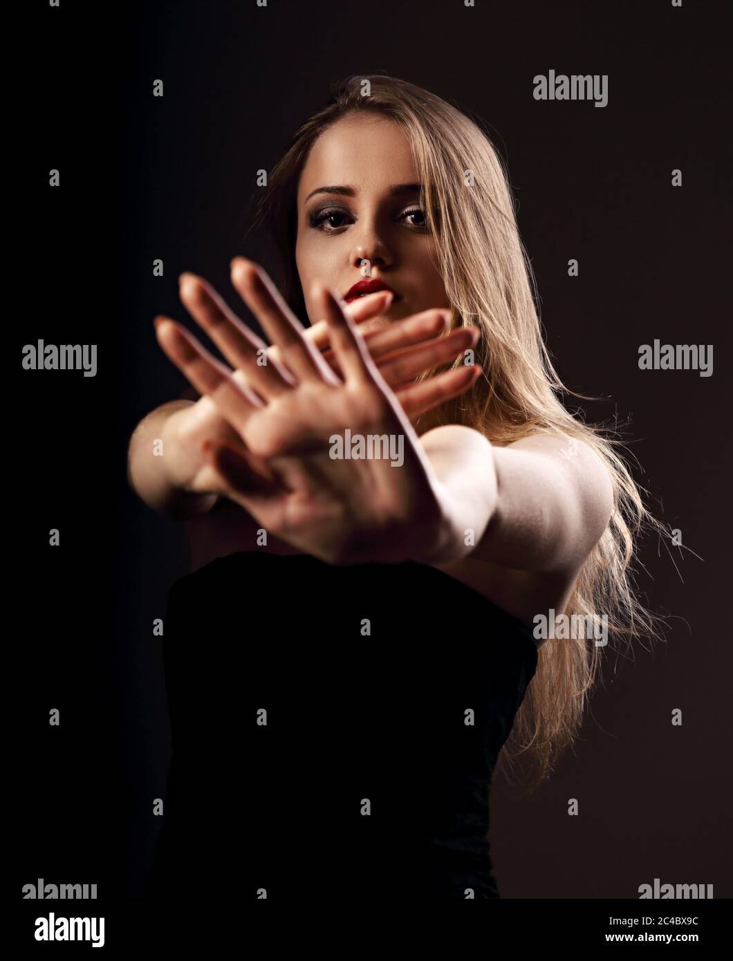 Angry young female blond model showing the hands and signaling to stop ...