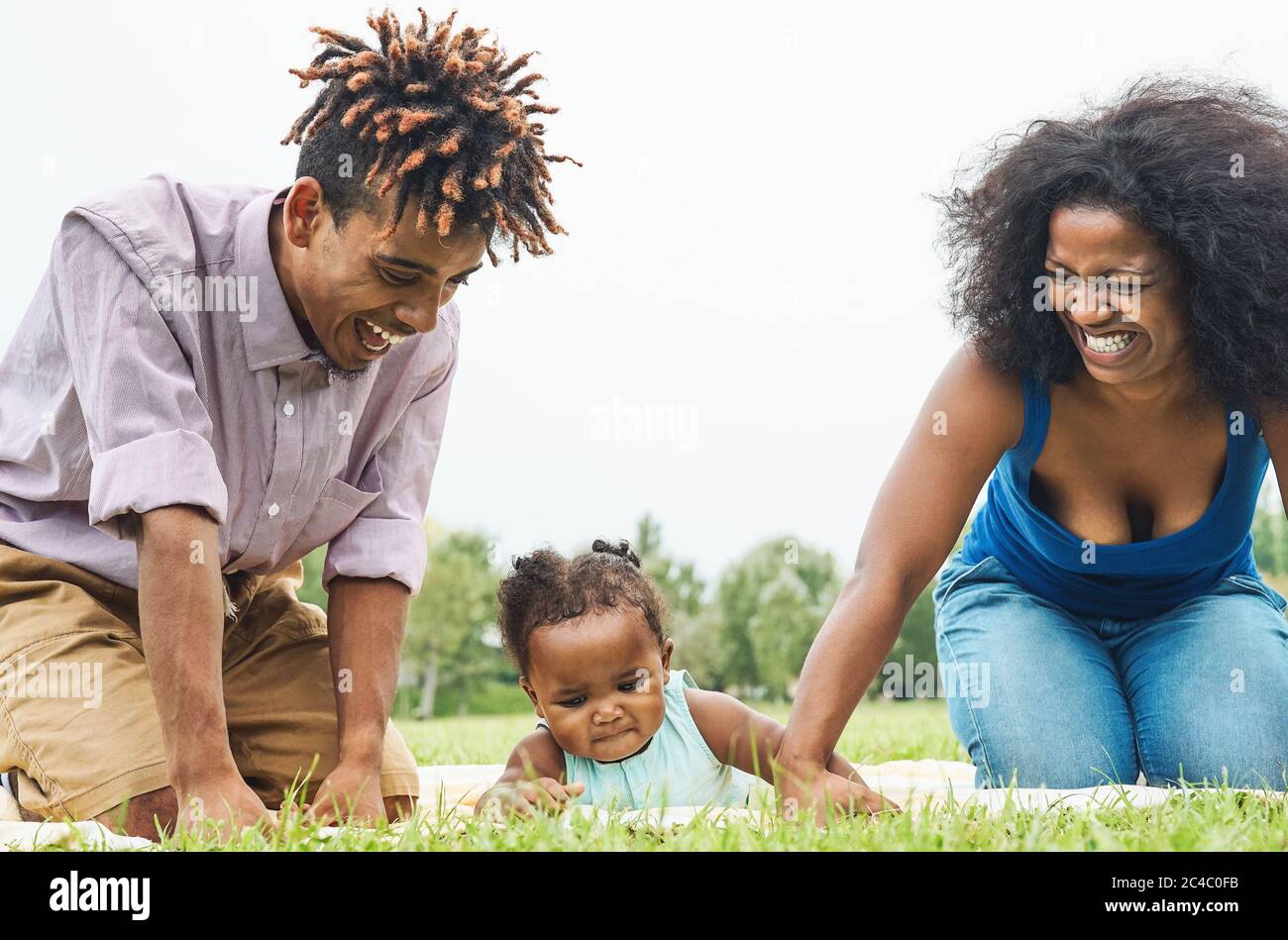 Happy African Family Having Fun Together In Public Park Black Father And Mother Holding Hand happy-african-family-having-fun-together-in-public-park-black-father-and-mother-holding-hand