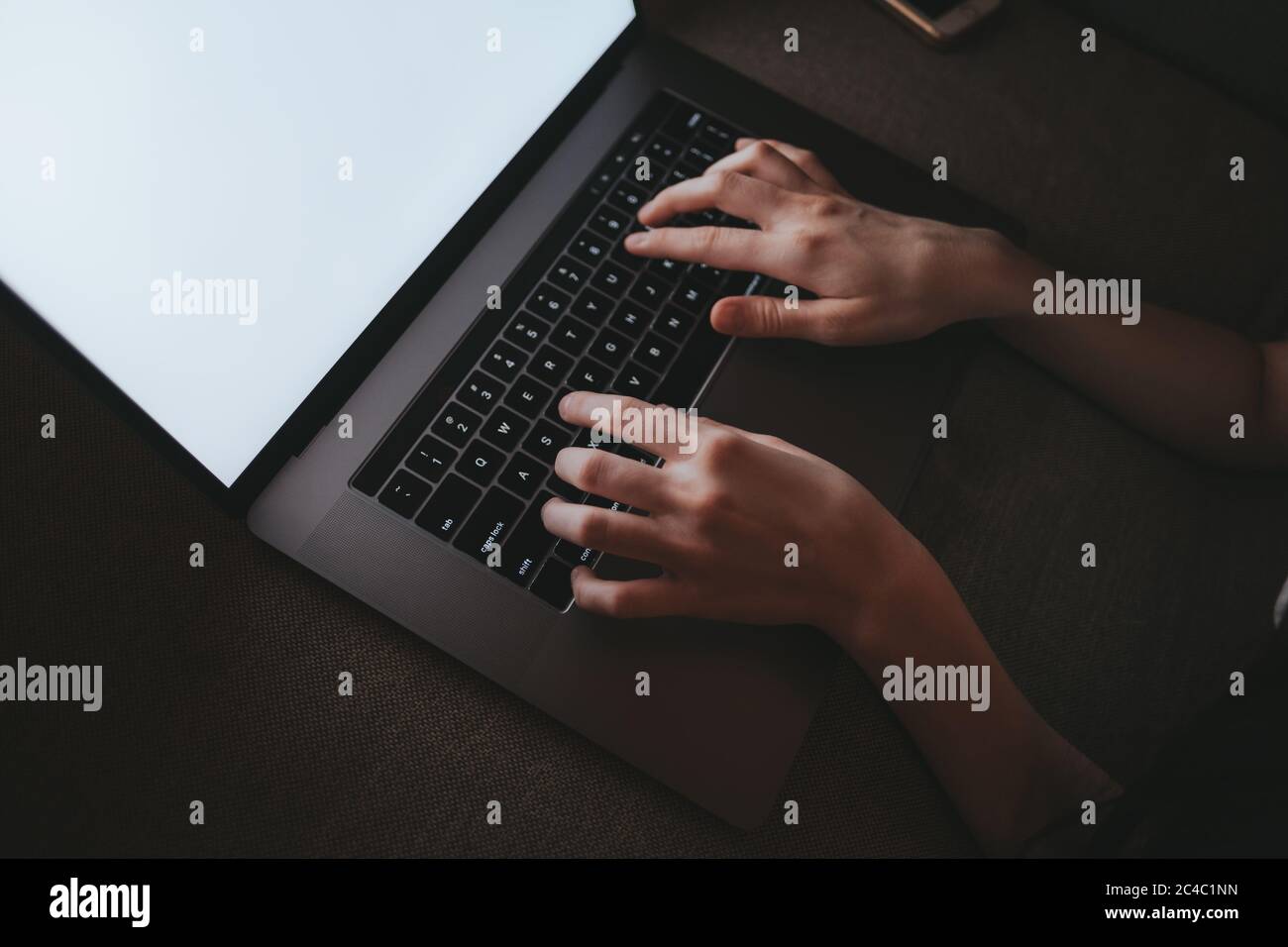 Woman is typing on a laptop keyboard while lying on a sofa at home in ...
